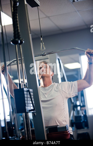 Middle-aged man pulling weight machine at gym Stock Photo - Alamy