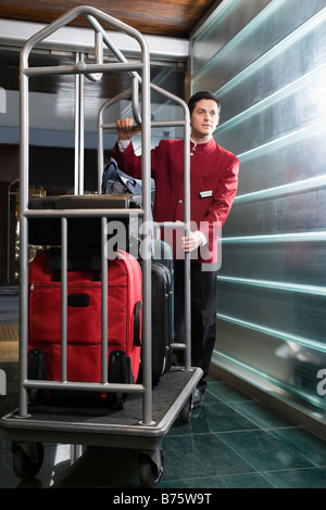 Waiter carrying luggage in a luggage rack Stock Photo - Alamy