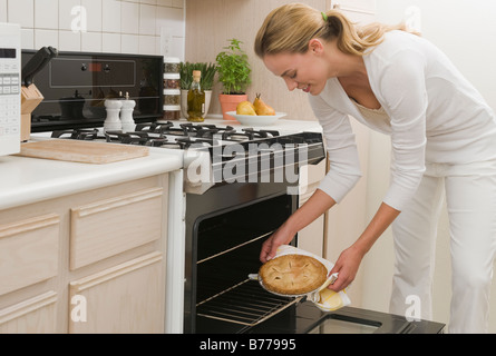 Woman removing pie from oven Stock Photo - Alamy