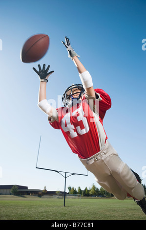 Football player mid-air reaching for football Stock Photo - Alamy
