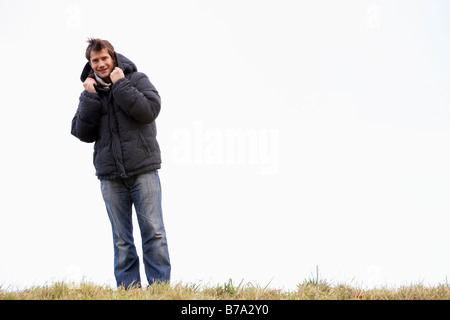Smiling man standing in a park, holding a mobile phone and clenching ...