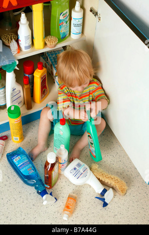 A child is playing with chemical cleaning products under the sink in ...