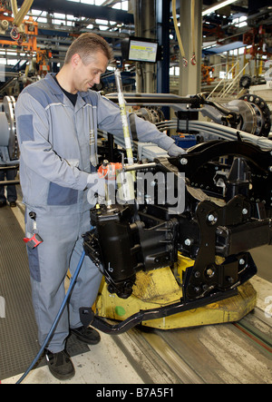Worker during axle assembly in the underbody of a truck, manufacture ...
