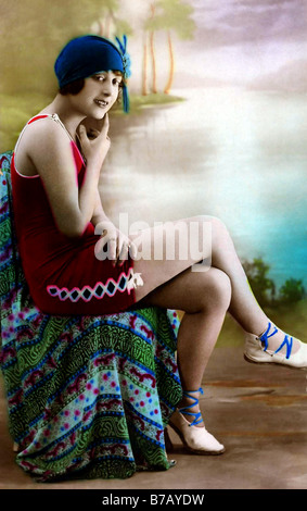 Smiling young woman in a swimsuit holds a cut grapefruit on a striped ...
