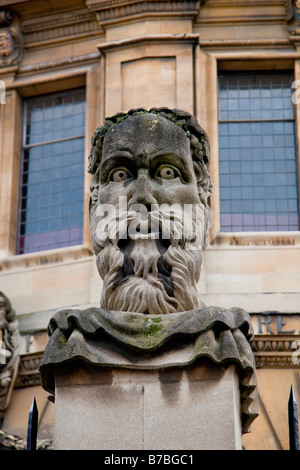 A scary faced stone head gargoyle on the wall surrounding the ...