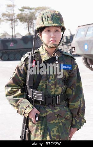 Portrait of female soldier standing with rifle against white background ...
