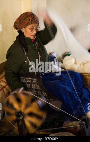 Skilled weaver weaving woman carpet on loom traditional dress knot tie ...