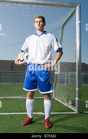 Full length portrait of a footballer holding a ball and standing in ...