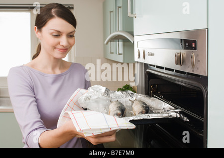 Smiling brunette woman cooking fish in home kitchen Stock Photo - Alamy