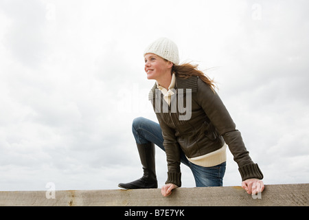 Woman climbing over over wall Stock Photo - Alamy