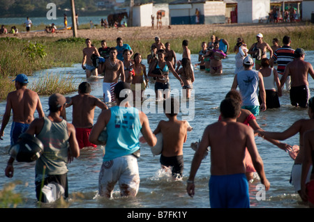 People walk through water to reach a river beach with a small number of ...