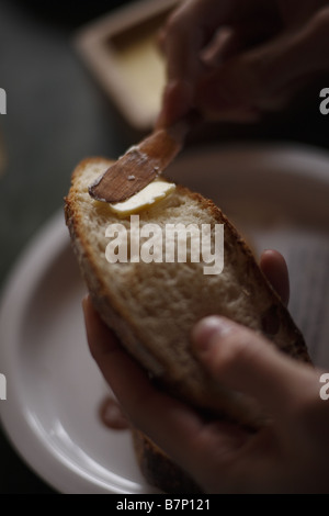 Close-up of a person spreading butter on bread slices using a spoon ...