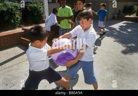 Boys fight over ball on playground Stock Photo - Alamy