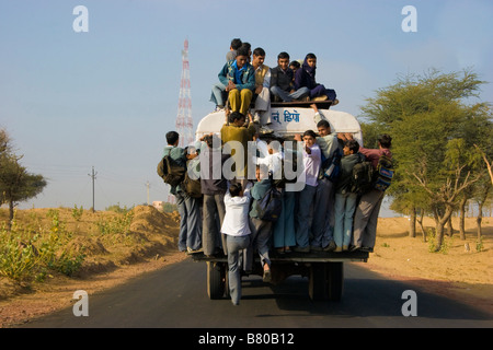 Overloaded public transport bus carrying people on top and hanging out ...