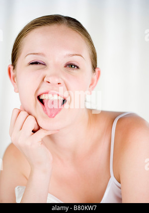 Young woman looking at camera while scrunching her nose, on white ...