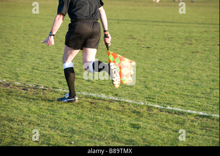 Linesman runs along touchline of football pitch Stock Photo - Alamy