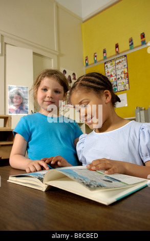 Young girls are sitting at the desk and reading text in the classroom ...