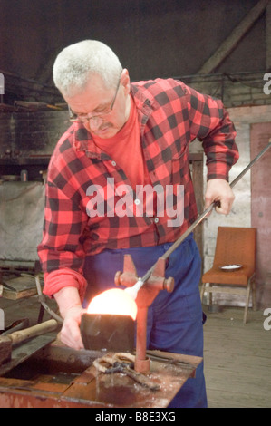Traditional glassblowing worker shaping liquid glass. The Details and ...