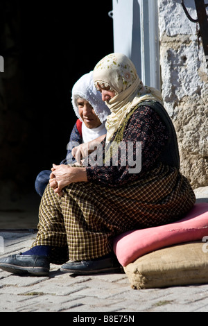 An elderly Turkish woman in a headscarf surveys the activity on the ...