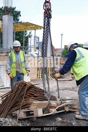 men using a lift and a crane to move big, heavy metal objects like pips ...