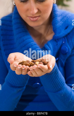 Attractive young woman eating walnuts in the park. Healthy food concept ...