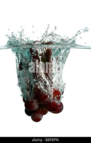 Close up of red grapes falling into water with copy space on black ...