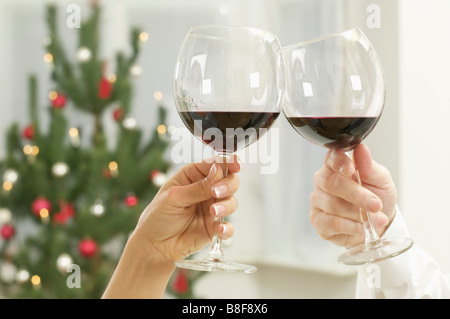 Two people chinking red wine glasses Stock Photo - Alamy