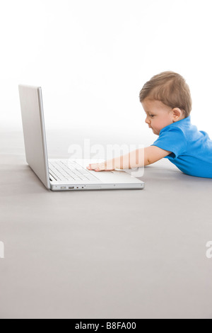 Funny baby boy playing with laptop computer work from home in cozy room ...