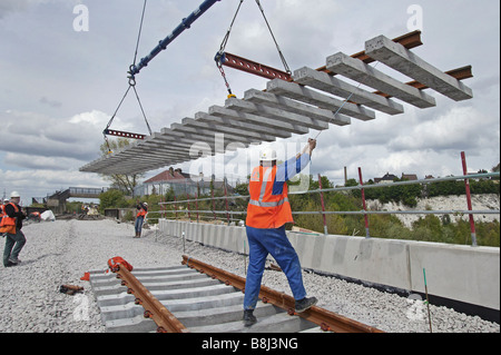 Rail contractors lowering a section of prefabricated track with rails ...