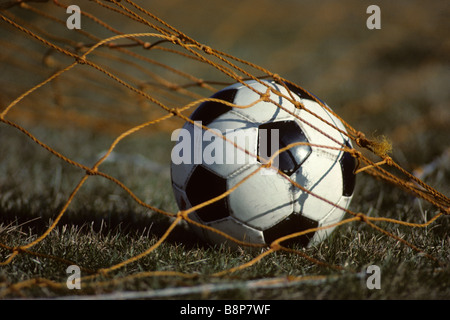 Soccer ball in the net on brown background Stock Photo - Alamy