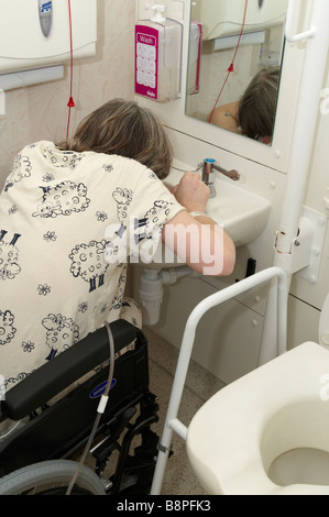 Woman washing face and freshening up in NHS hospital toilet sitting in ...