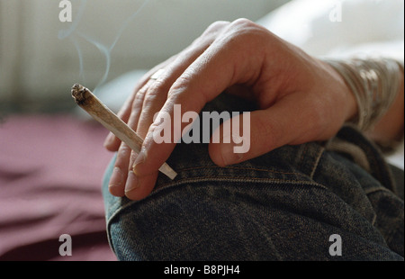 Detail of the hand of a smoking man holding a burning cigar, isolated ...
