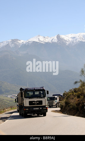 Heavy freight trucks and articulated lorries navigate along the unpaved ...