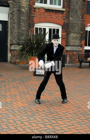 Man mime in black suit sitting on swing. Mixed media Stock Photo - Alamy