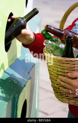 Man recycling glass. Throwing a glass bottle into a green recycling ...