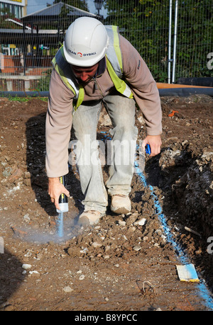 Construction worker marking out area for Jcb to dig trench Stock Photo ...