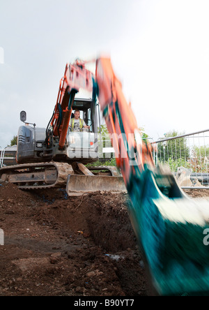 Jcb digging a trench on a construction site while a workman digs around ...