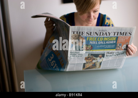 UK sunday newspaper reader reads The Sunday Times with free CD skyline ...