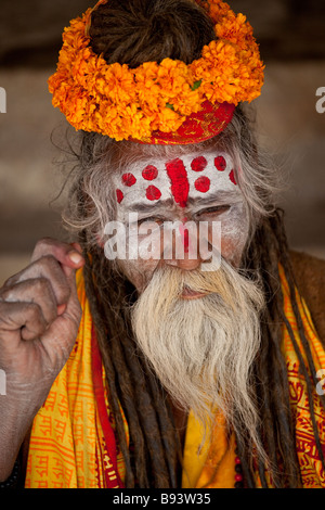A hindu sadhu (holy man), wearing traditional facial paint, smokes a ...