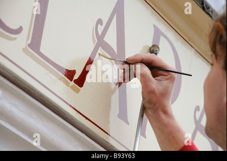 Sign painter Keith Pettit with a mahl stick at work on a shop sign in ...