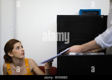 Exchanging documents two standing colleagues working in open office ...