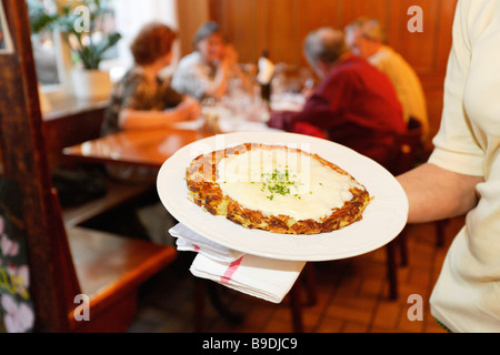 Woman serving the national dish Rosti in the restaurant Hasenburg Old ...