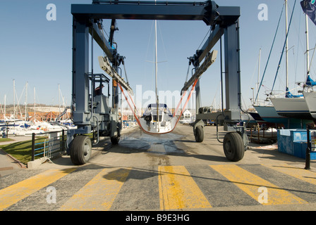 yacht being lowered into the water on a hoist in a marina Stock Photo ...