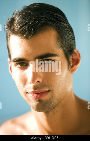 Portrait of smiling young man watching something in front of grey ...