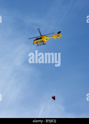 Rescue helicopter transporting injured people hanging on a rope Stock ...