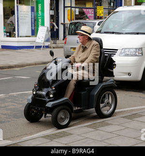 Man riding a 3 wheeled electric disabled mobility scooter in the UK ...