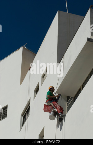 Worker abseiling painting exterior wall of Bauhaus style building in ...