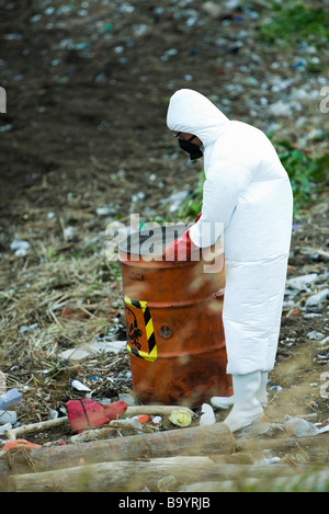 Person in protective suit carrying barrel of hazardous waste Stock ...