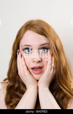 Portrait of a shocked redhead woman in dress holding alarm clock and ...