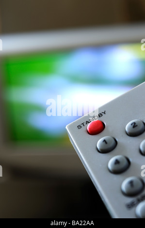 TV remote control with red standby button and television screen ...